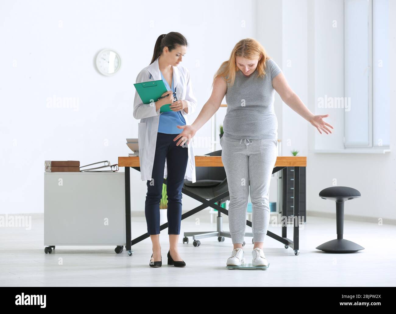 Young female doctor measuring weight of overweight woman in clinic ...