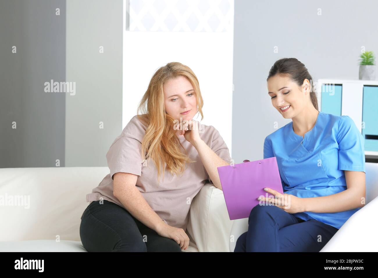 Young female doctor consulting overweight woman in clinic Stock Photo ...