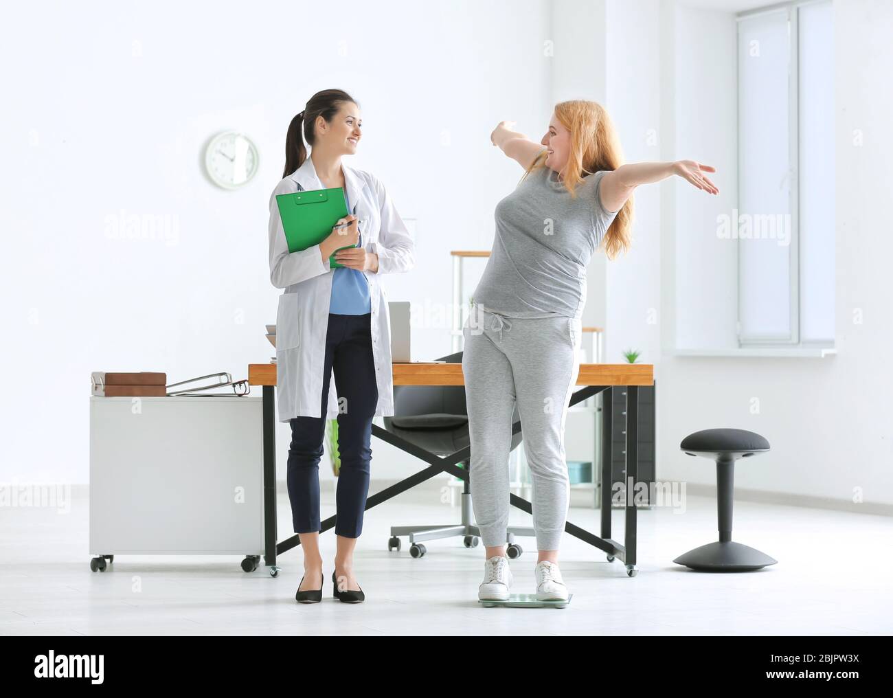 Young female doctor measuring weight of overweight woman in clinic ...