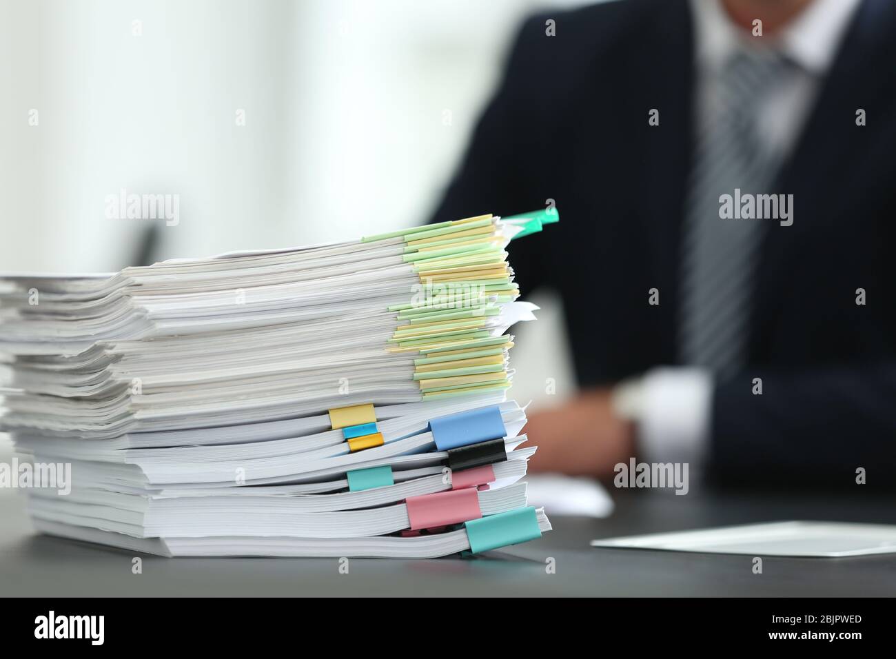 Stack of documents on table and blurred man in office Stock Photo - Alamy
