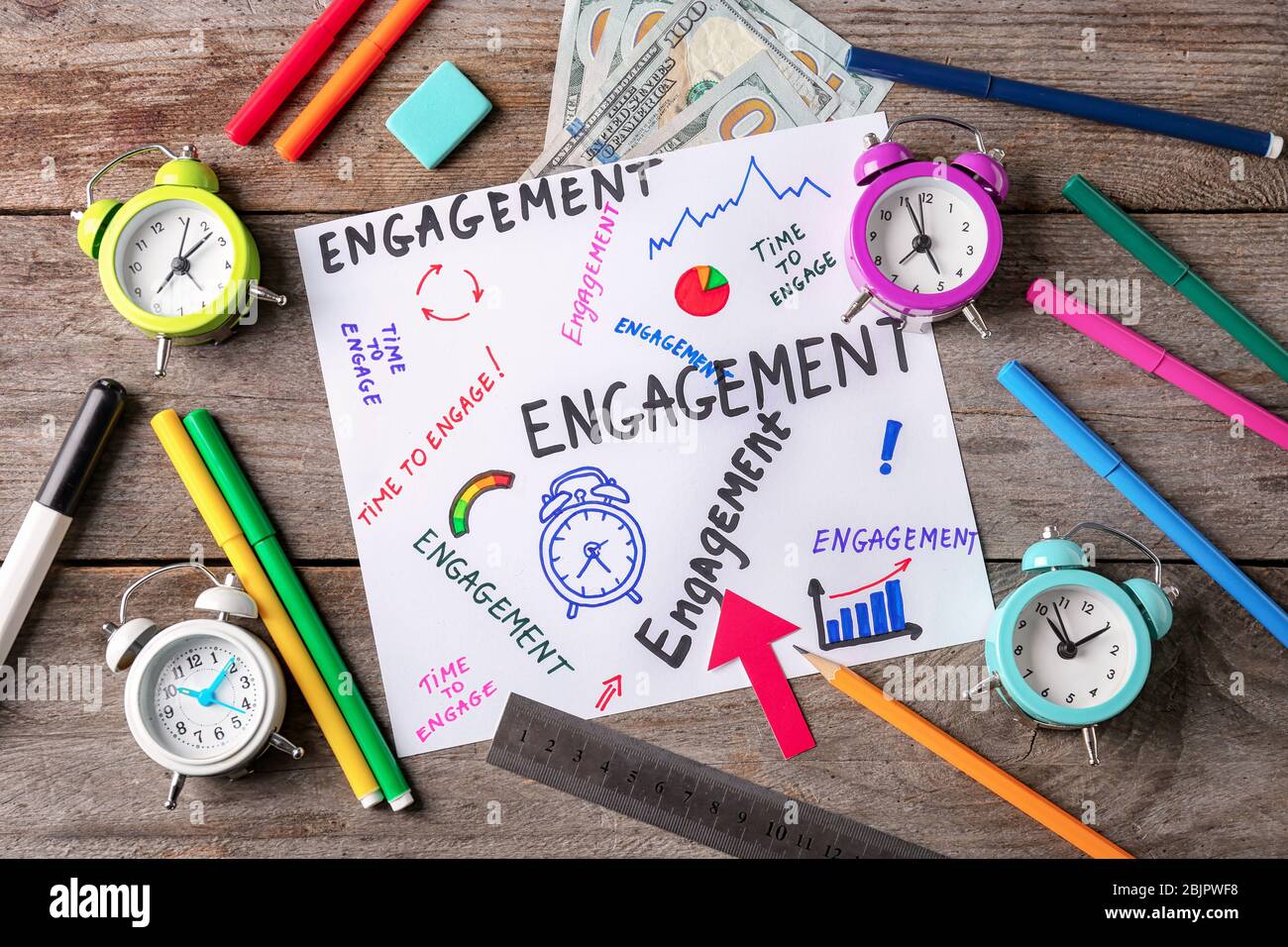Sheet of paper with written words ENGAGEMENT, clocks and markers on ...