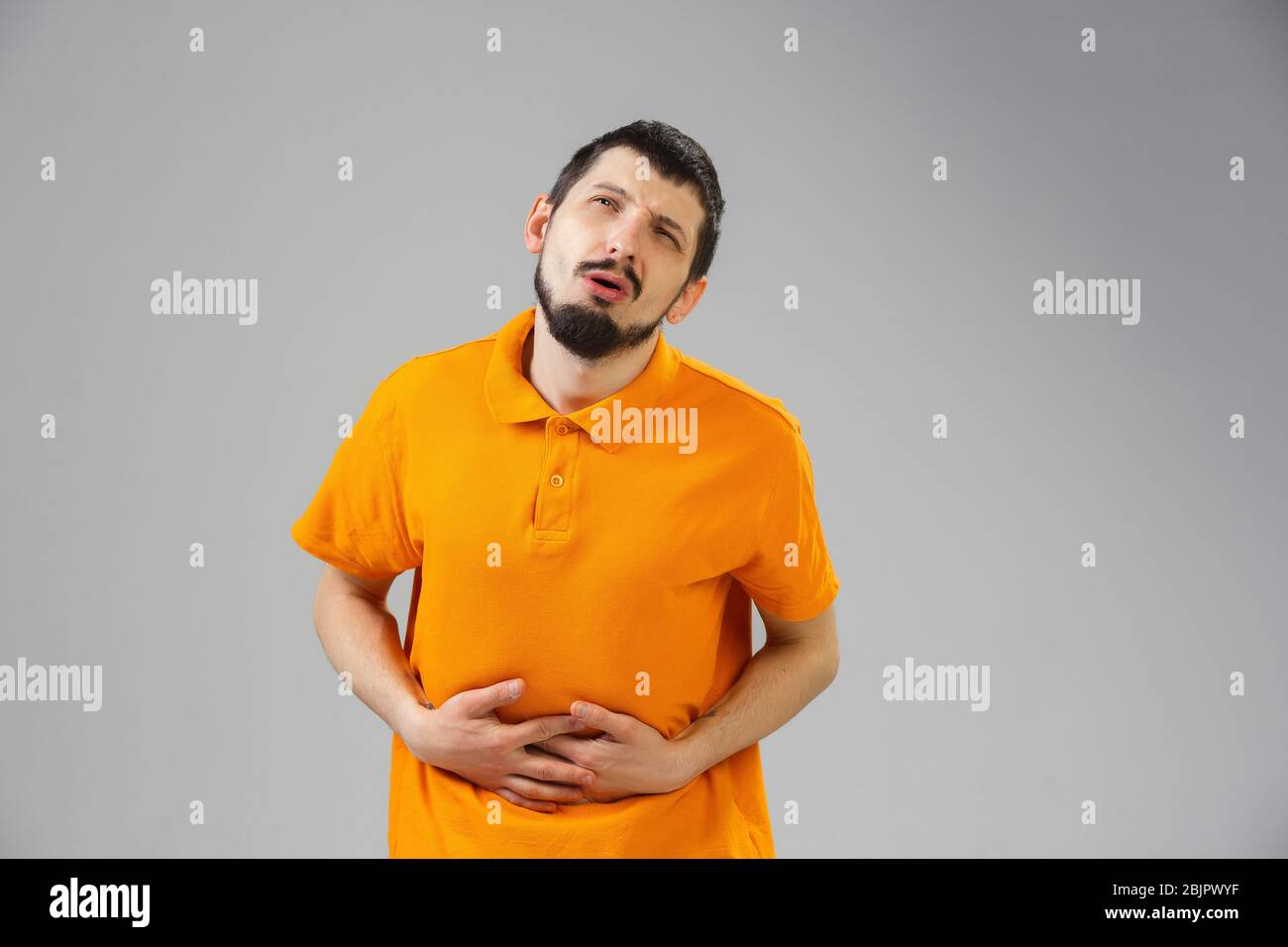 Young caucasian man suffers from abdominal pain, feels sick, ill and ...