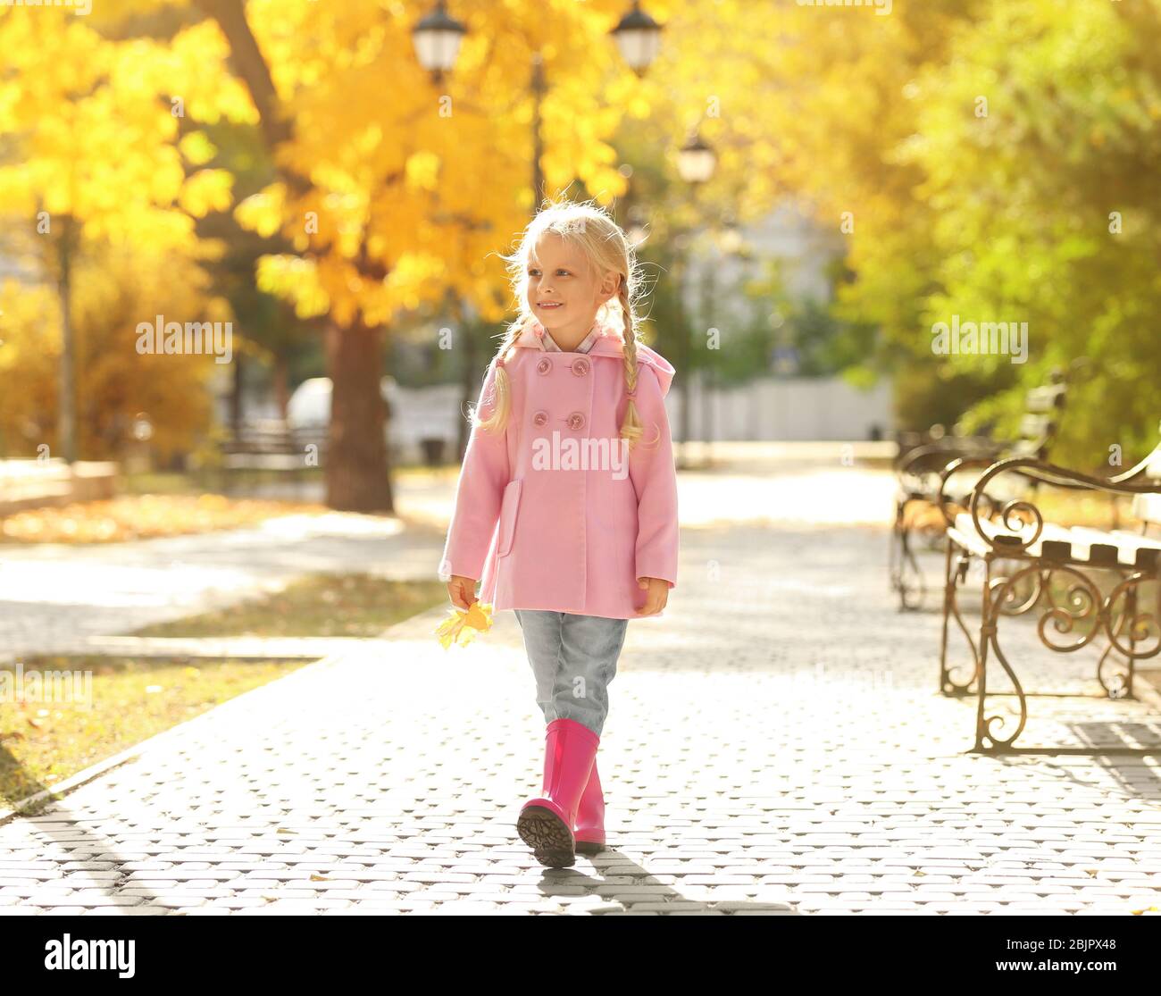 Cute little girl walking in autumn park Stock Photo - Alamy