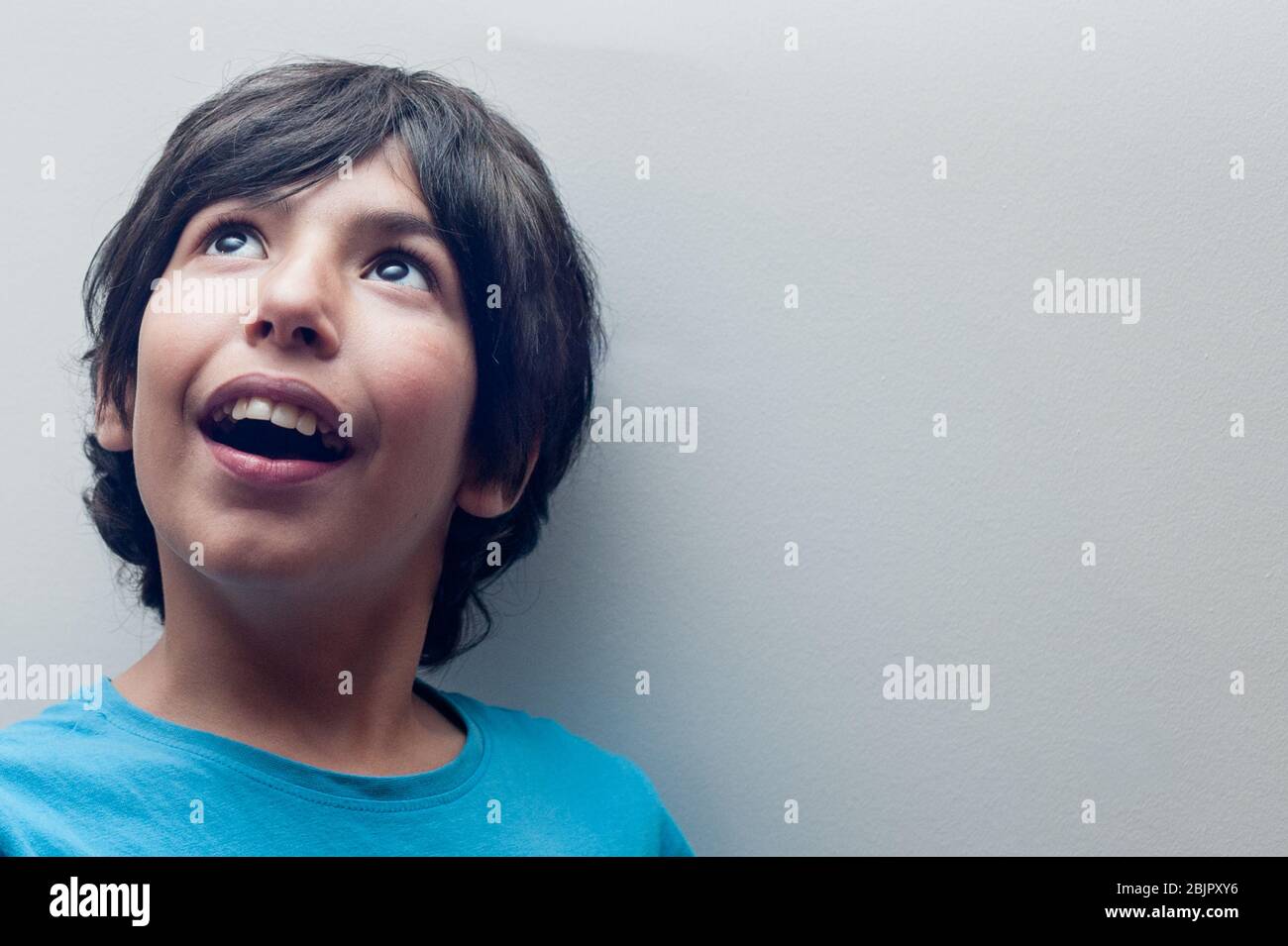 young boy happily looking up in a white background. Great copy space ...