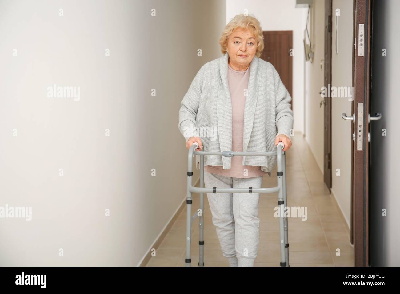 Elderly woman with walking frame in corridor Stock Photo - Alamy