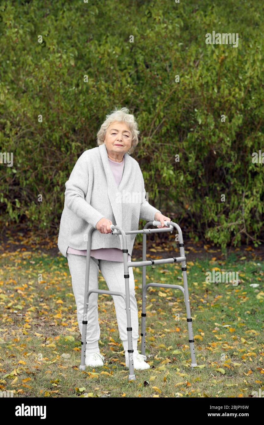 Elderly woman with walking frame outdoors Stock Photo - Alamy