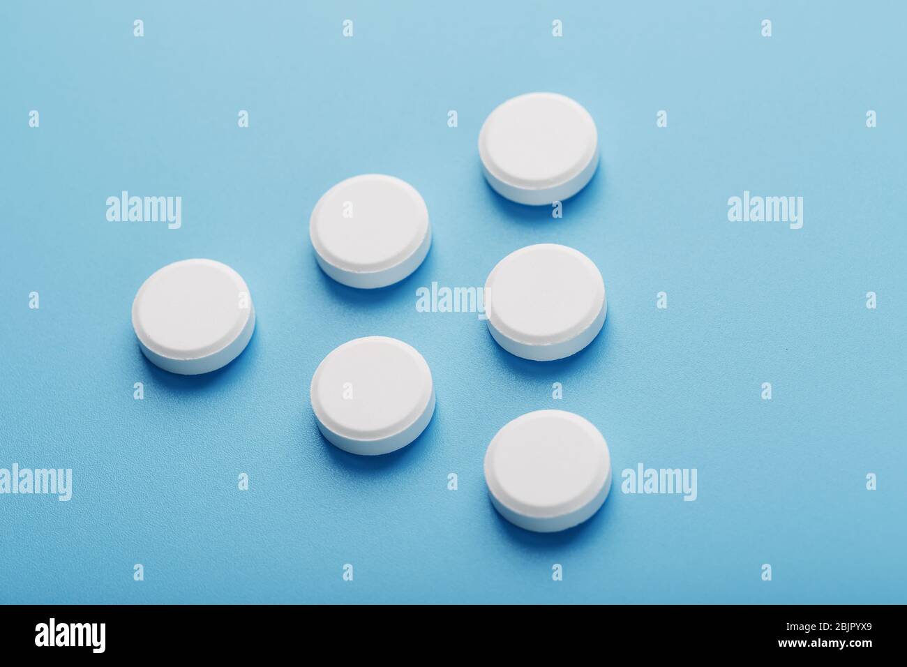 White medicinal tablets in the shape of a pyramid on a blue background ...
