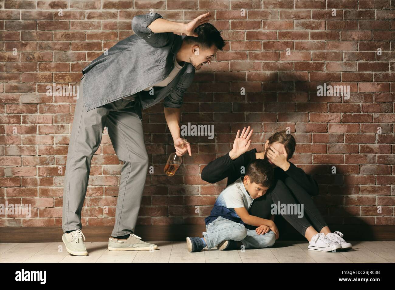Drunk man threatening his wife and son against brick wall Stock Photo ...
