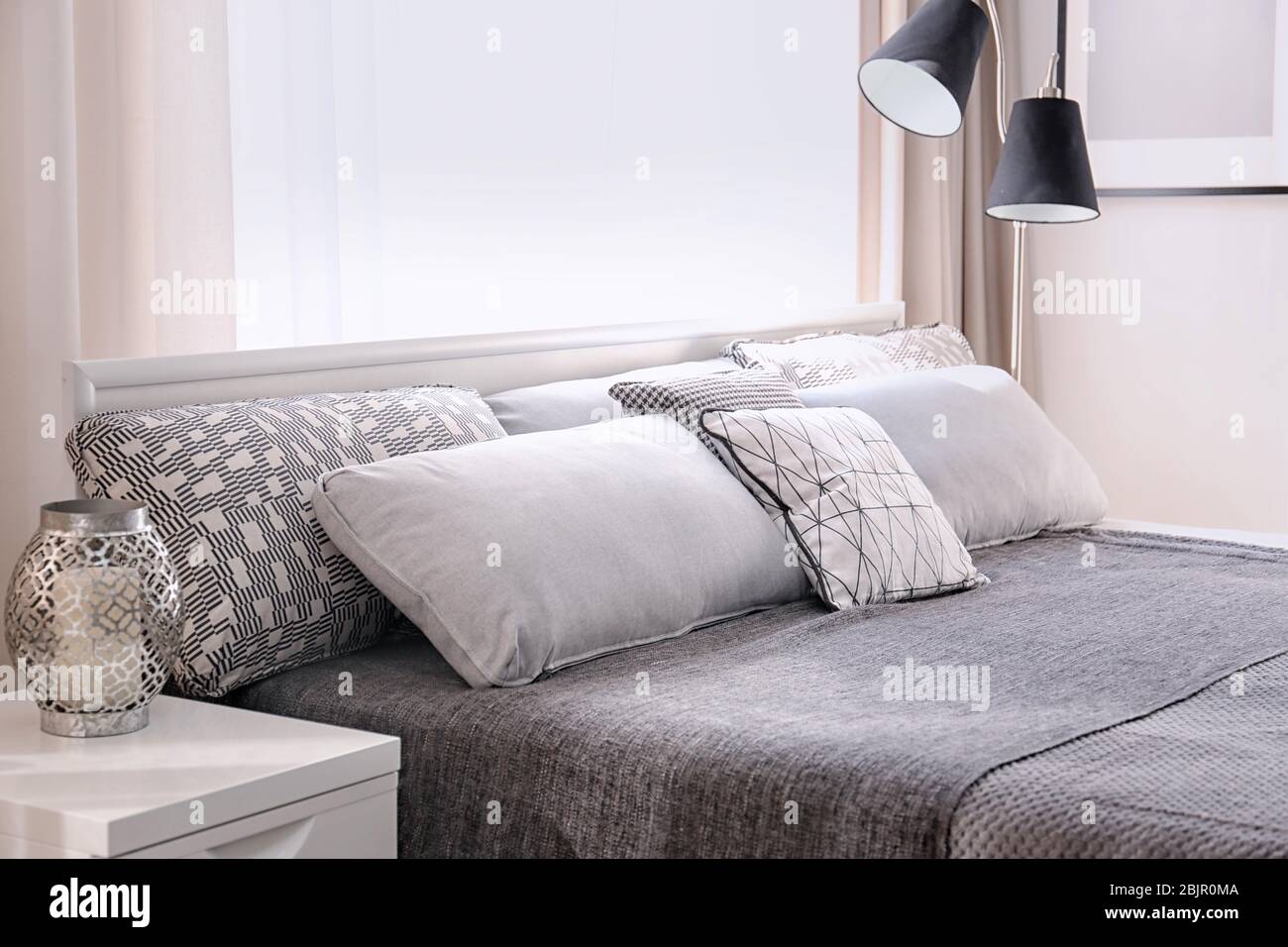 Comfortable bed with pillows in light room Stock Photo - Alamy