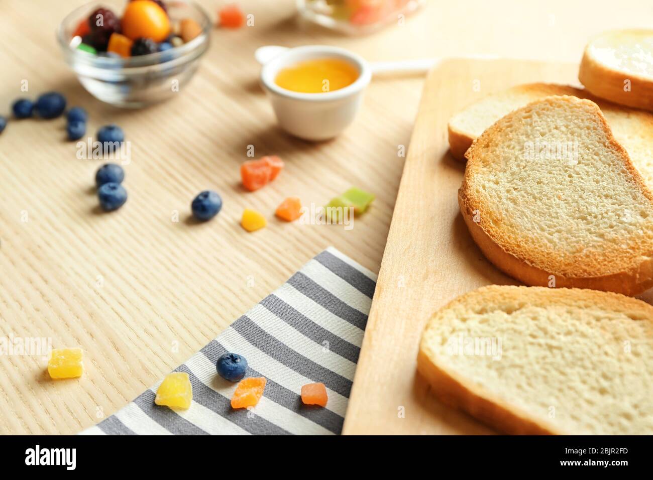 Board with fresh crispy toasts on wooden table Stock Photo - Alamy