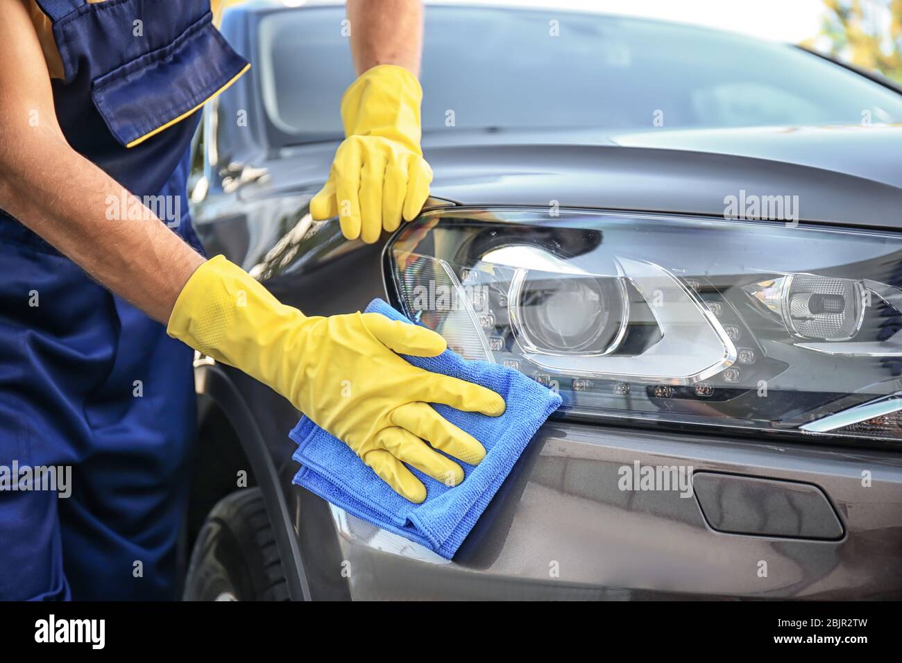 Man cleaning car headlight with rag outdoors Stock Photo - Alamy