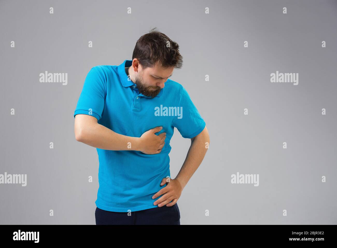 Young caucasian man suffers from side pain, feels sick, ill and ...