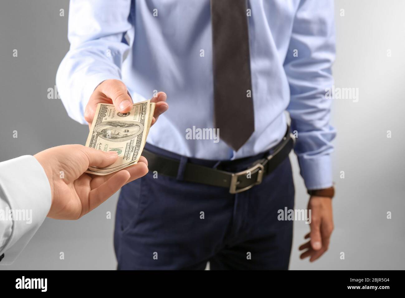 Woman giving money to man on light background Stock Photo - Alamy