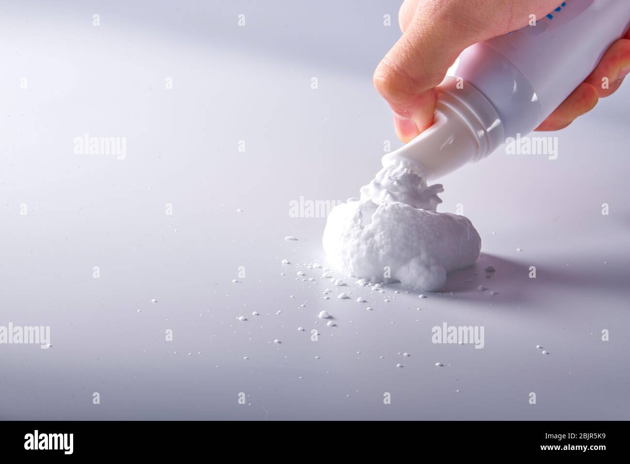 Moment close-up of hand pressing out shaving foam Stock Photo - Alamy
