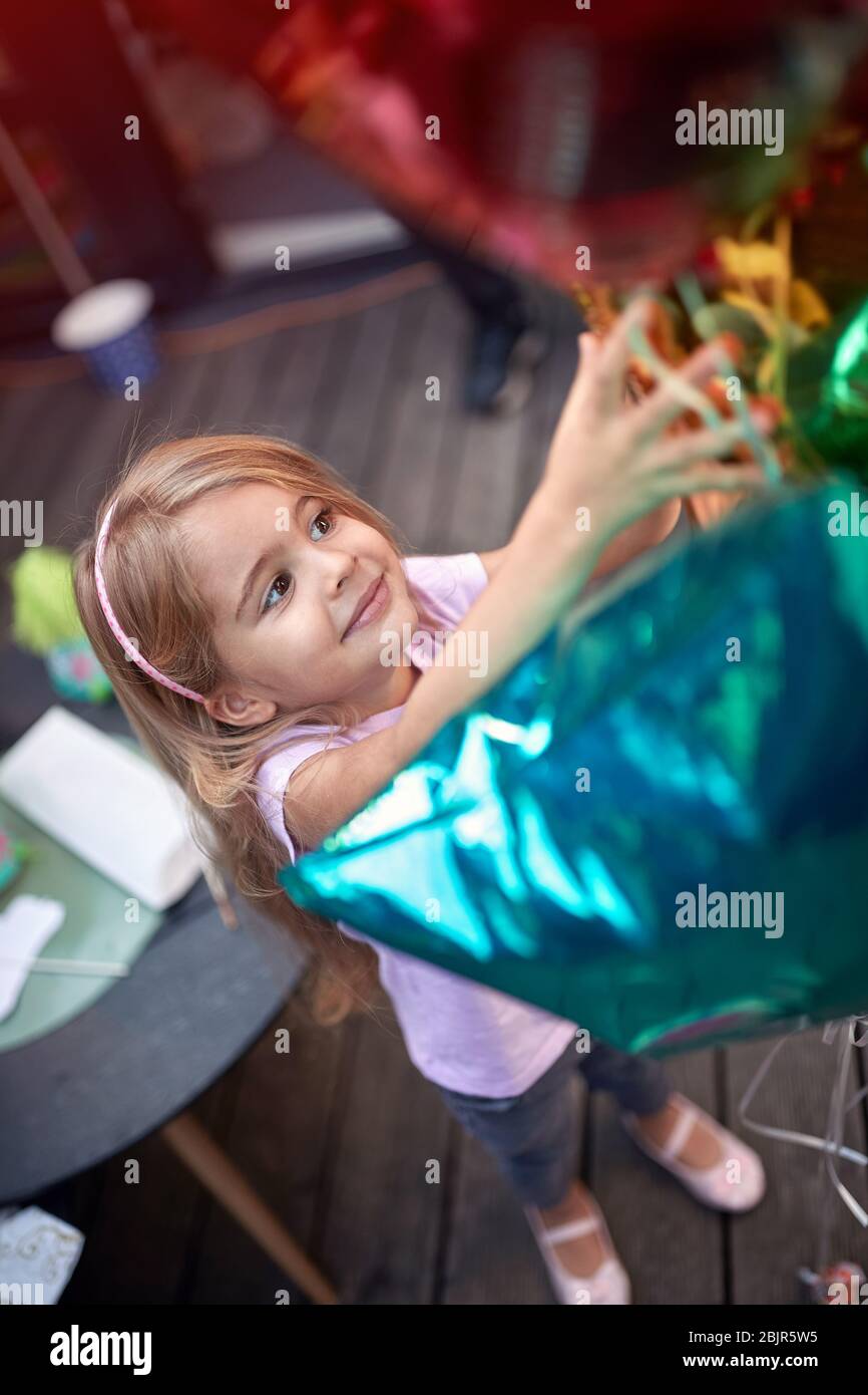 top view of a beautiful little girl reaching balloons, smiling Stock ...