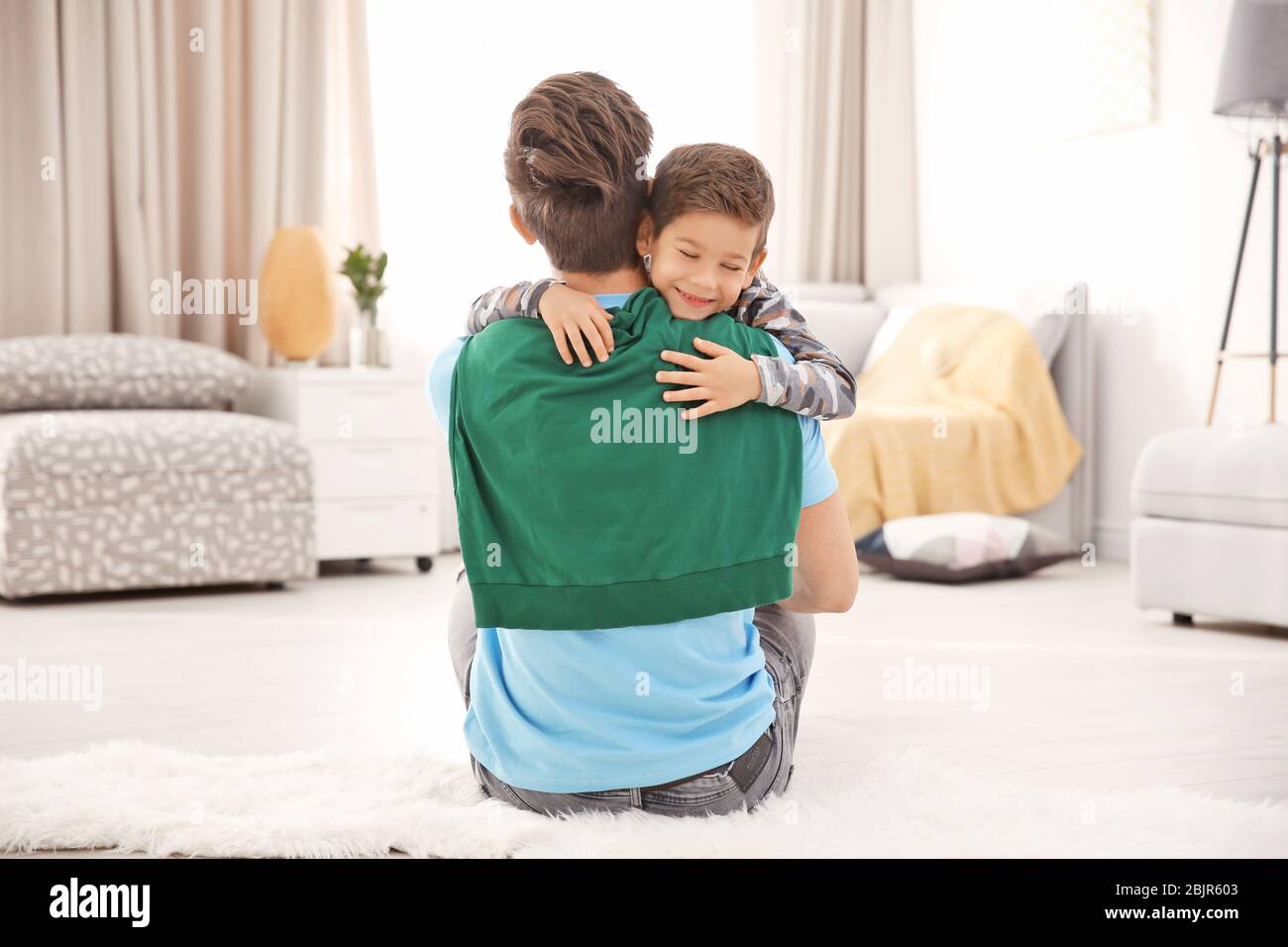 Cute little boy hugging his father at home Stock Photo - Alamy