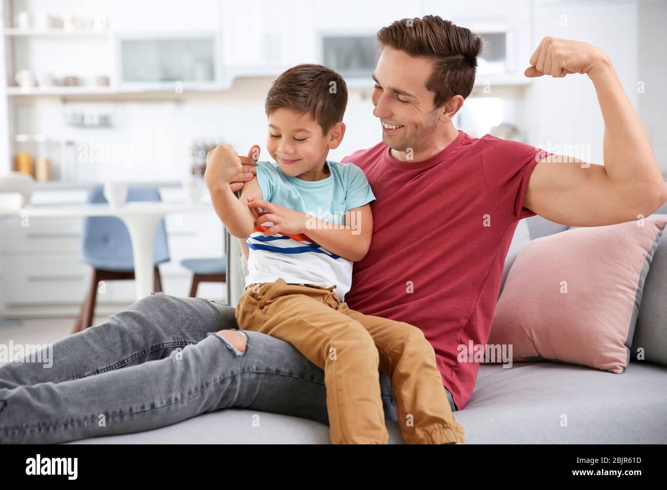 Father and his little son compare size of their biceps at home Stock ...