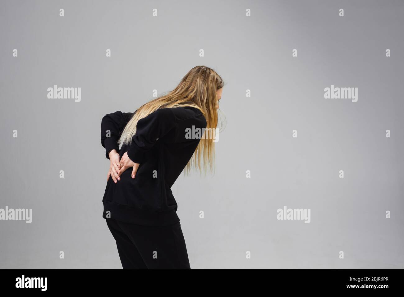 Young caucasian woman suffers from back pain, feels sick, ill and ...