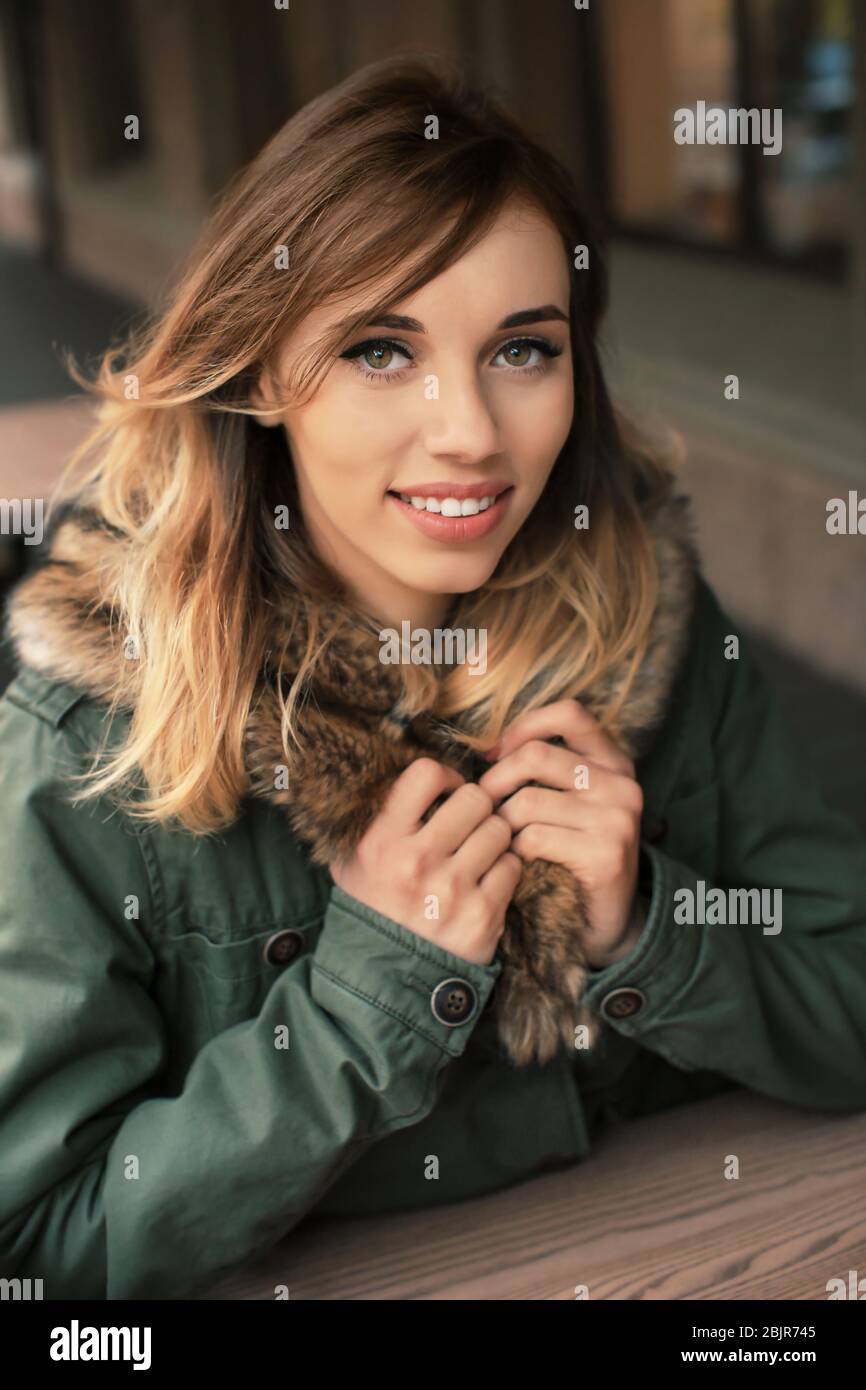 Attractive smiling woman in jacket with fur collar in open air cafe ...