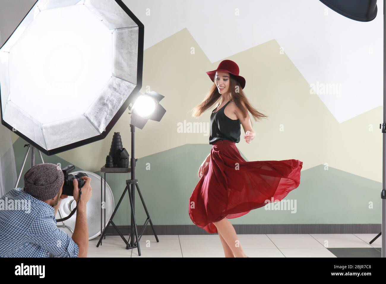 Beautiful young model posing for professional photographer in studio ...