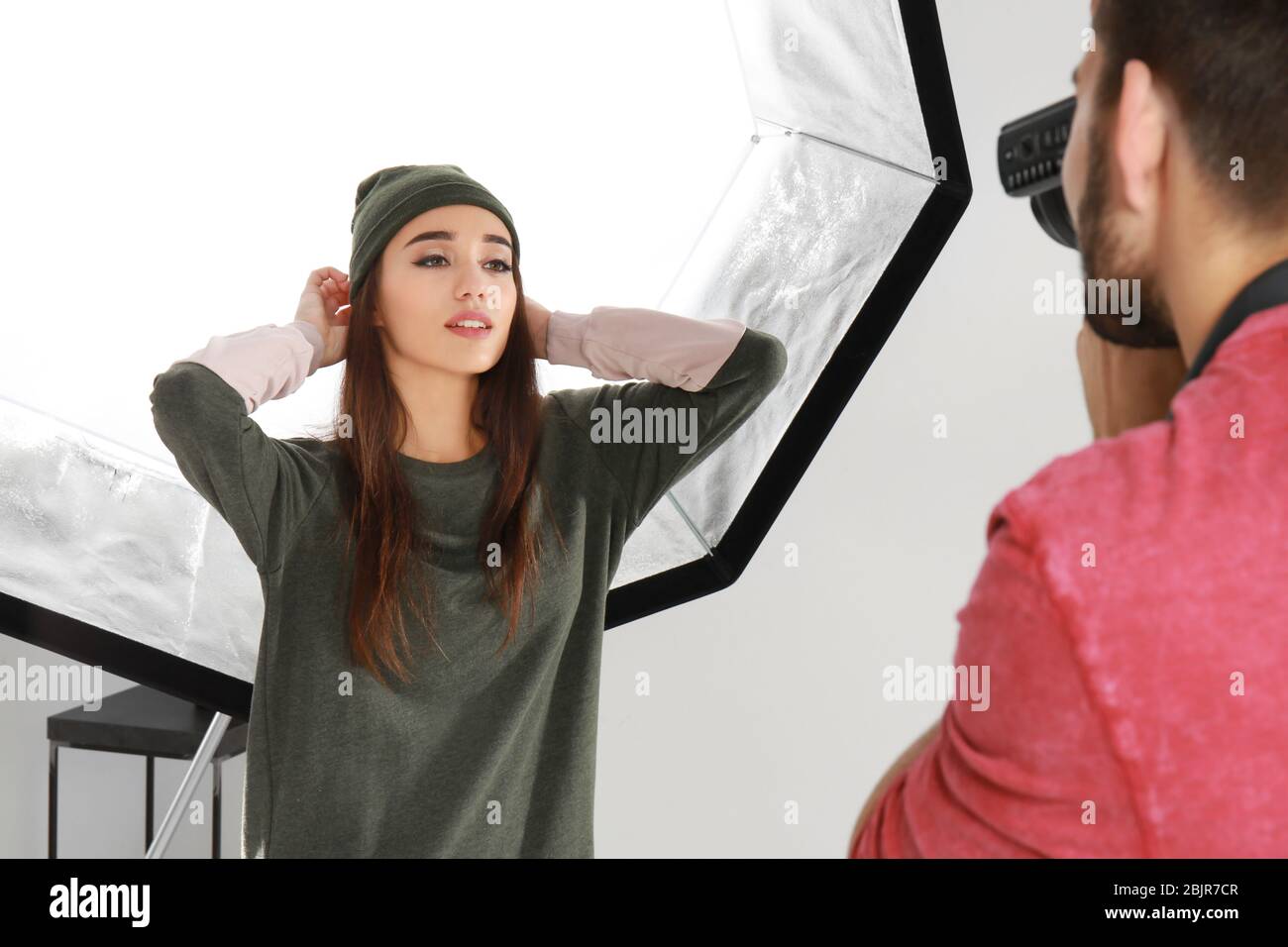 Beautiful young model posing for professional photographer in studio ...