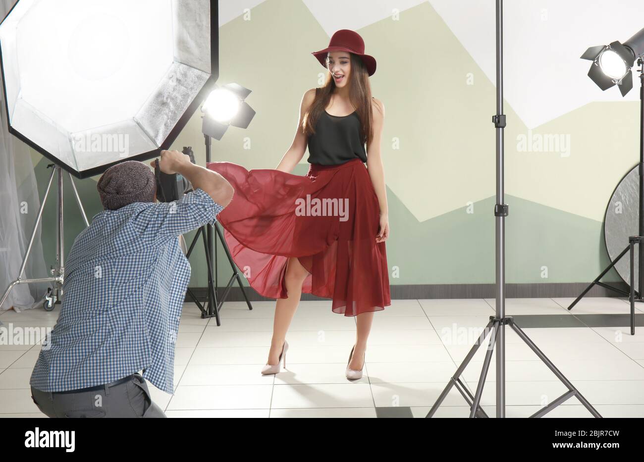 Beautiful young model posing for professional photographer in studio ...