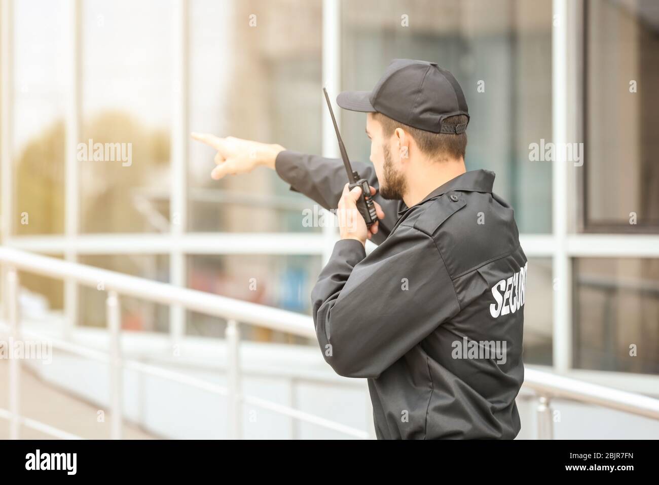 Male security guard using portable radio transmitter near building ...
