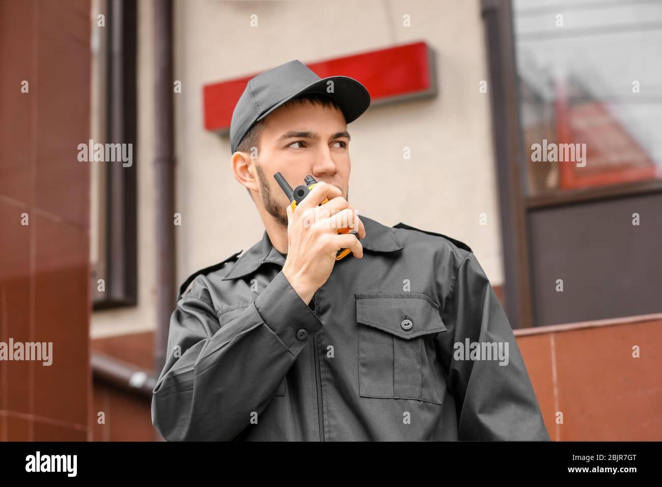 Male security guard using portable radio transmitter near building ...