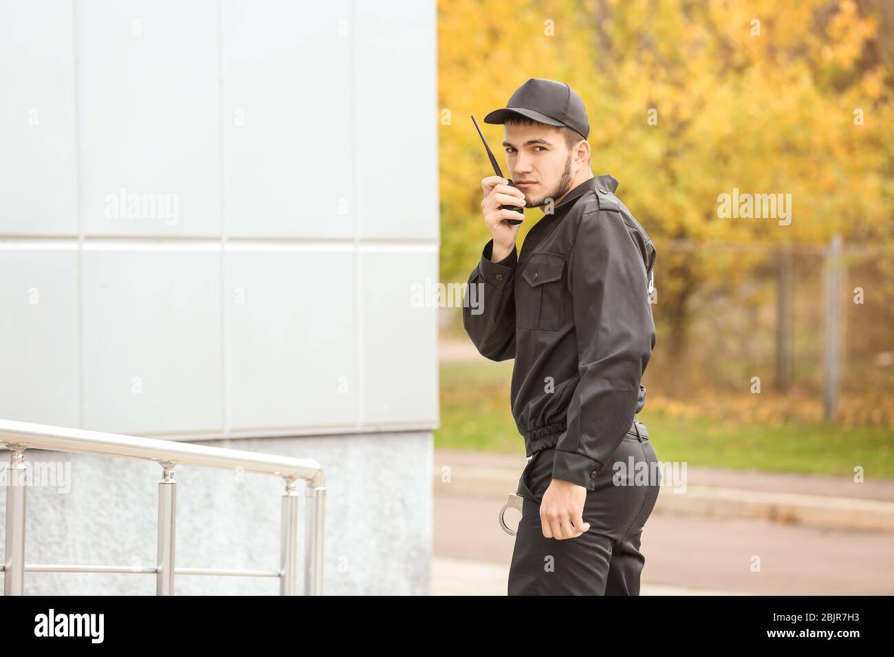 Male security guard using portable radio transmitter near building ...