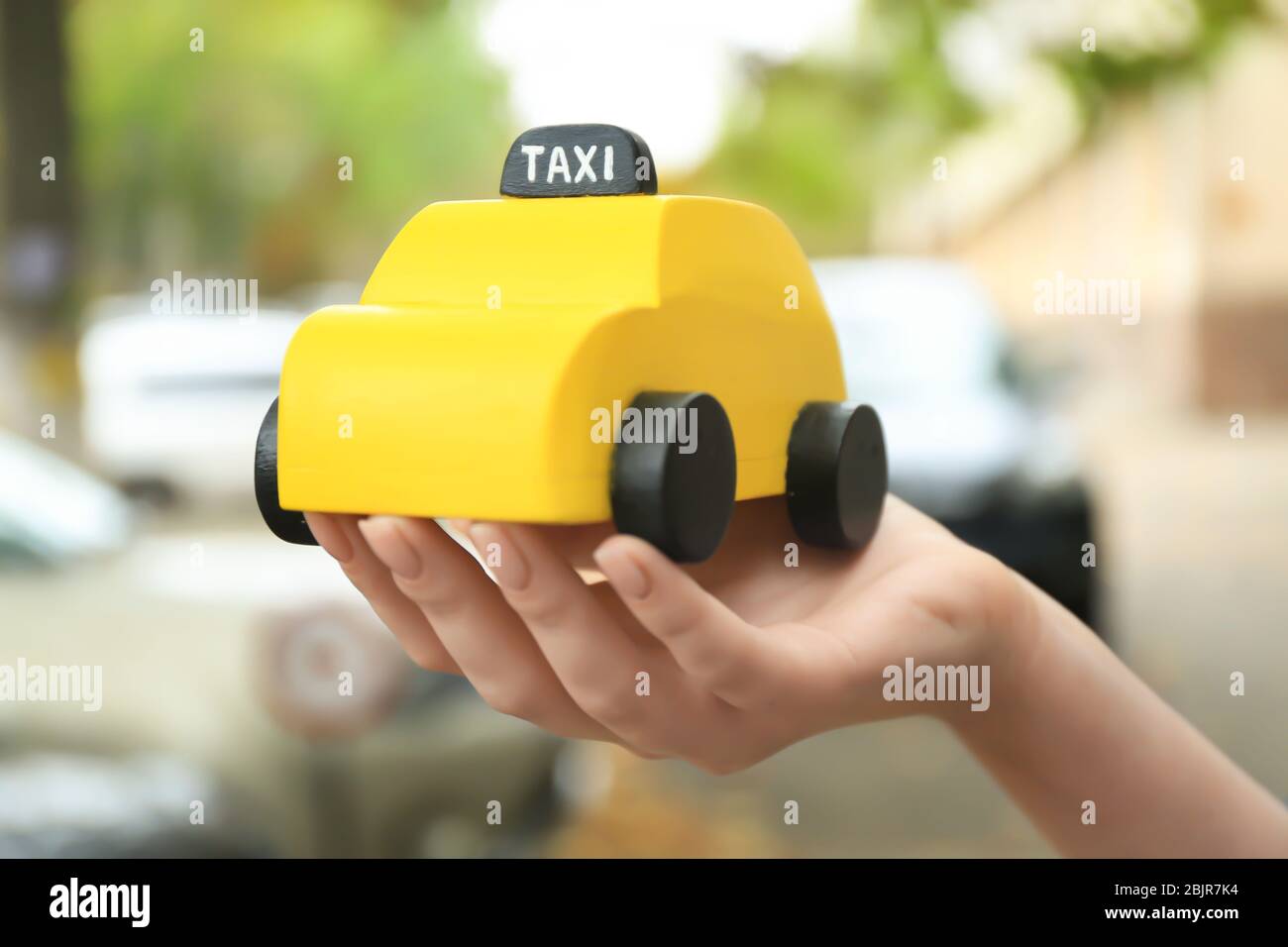 Woman holding yellow toy taxi cab outdoors, closeup Stock Photo - Alamy