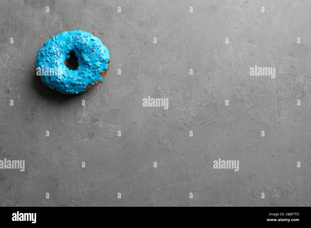 Blue donut with sprinkles on grey background Stock Photo - Alamy