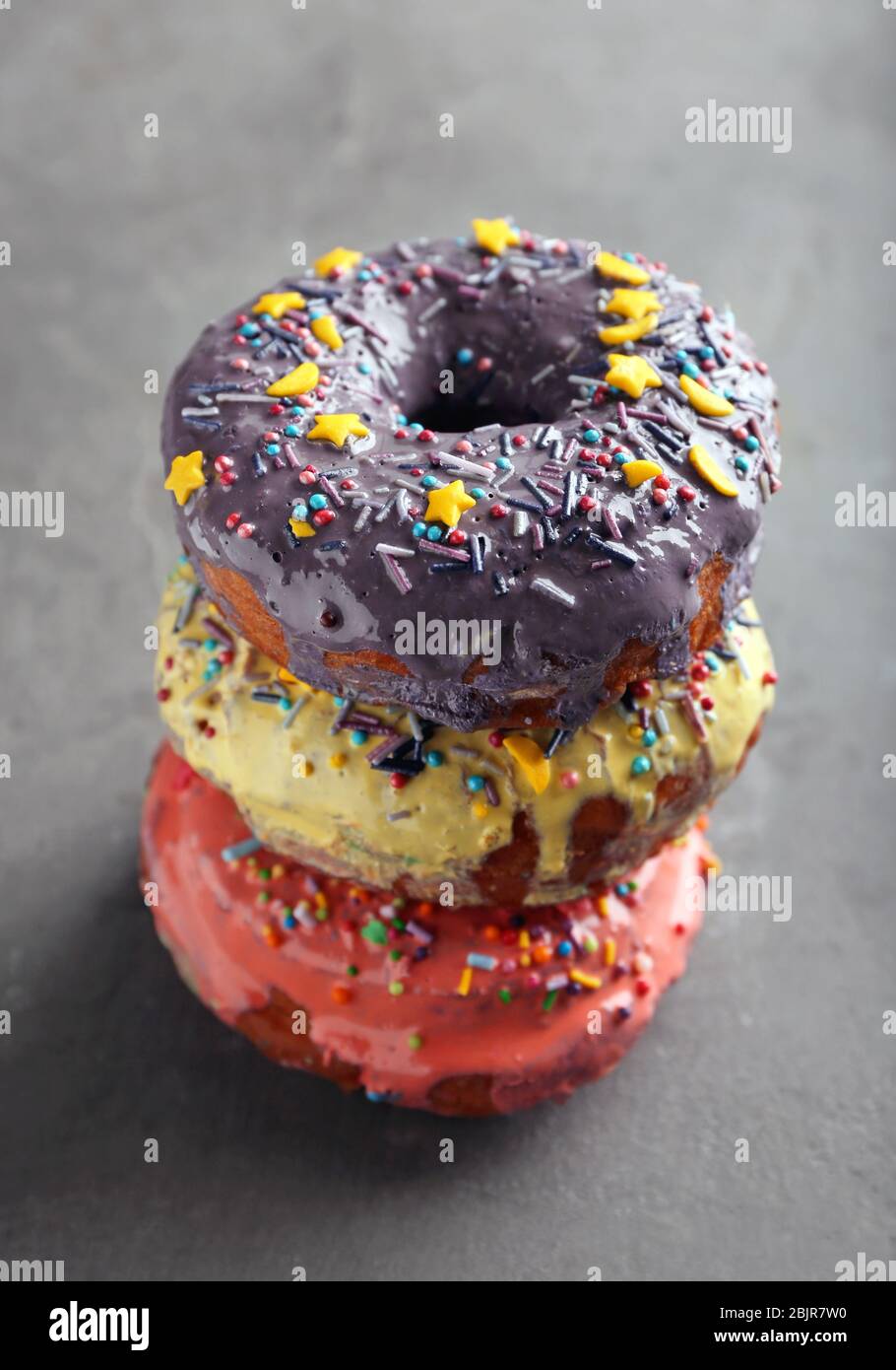 Colorful donuts with sprinkles on grey background Stock Photo - Alamy