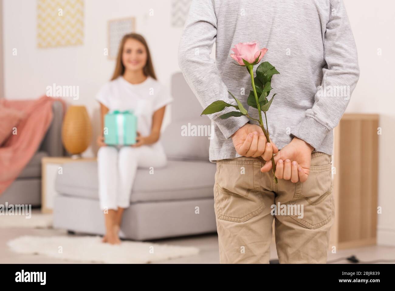 Cute little boy hiding flower for mother behind his back at home Stock ...