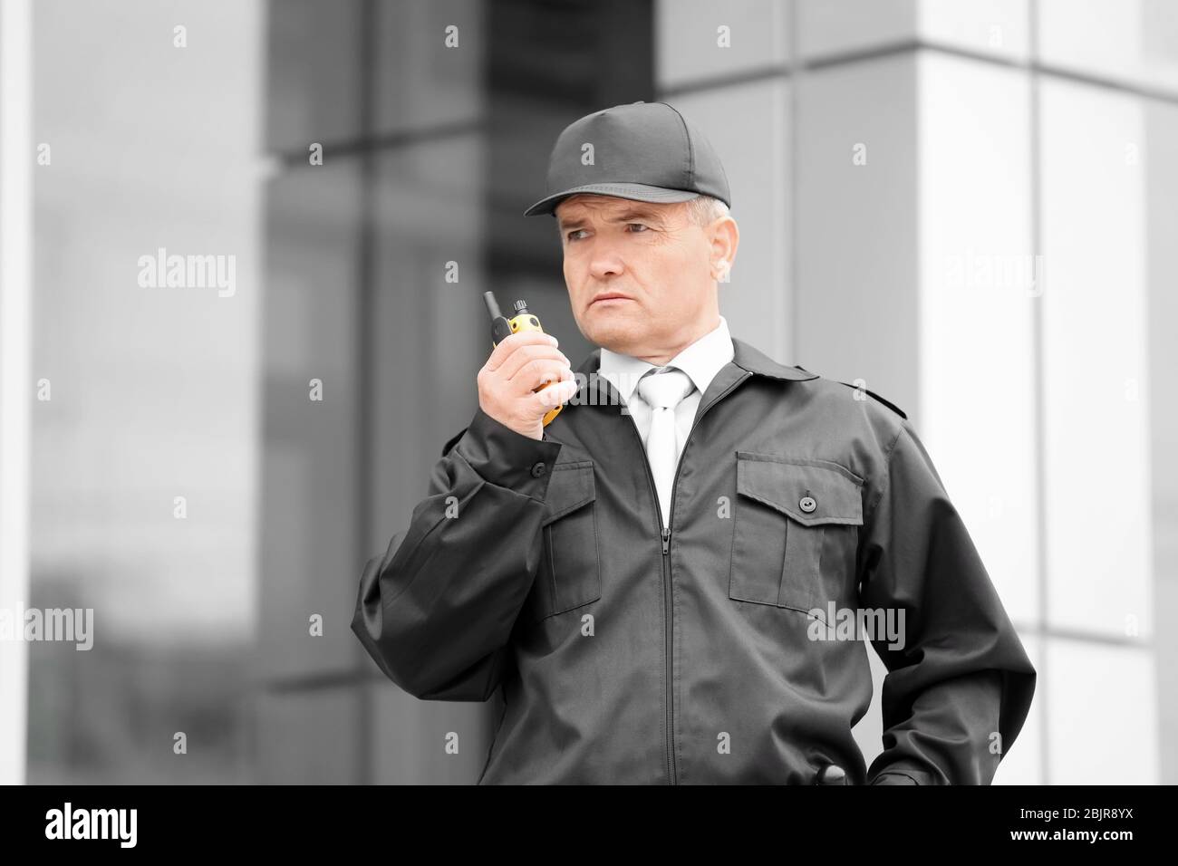 Male security guard using portable radio outdoors Stock Photo - Alamy