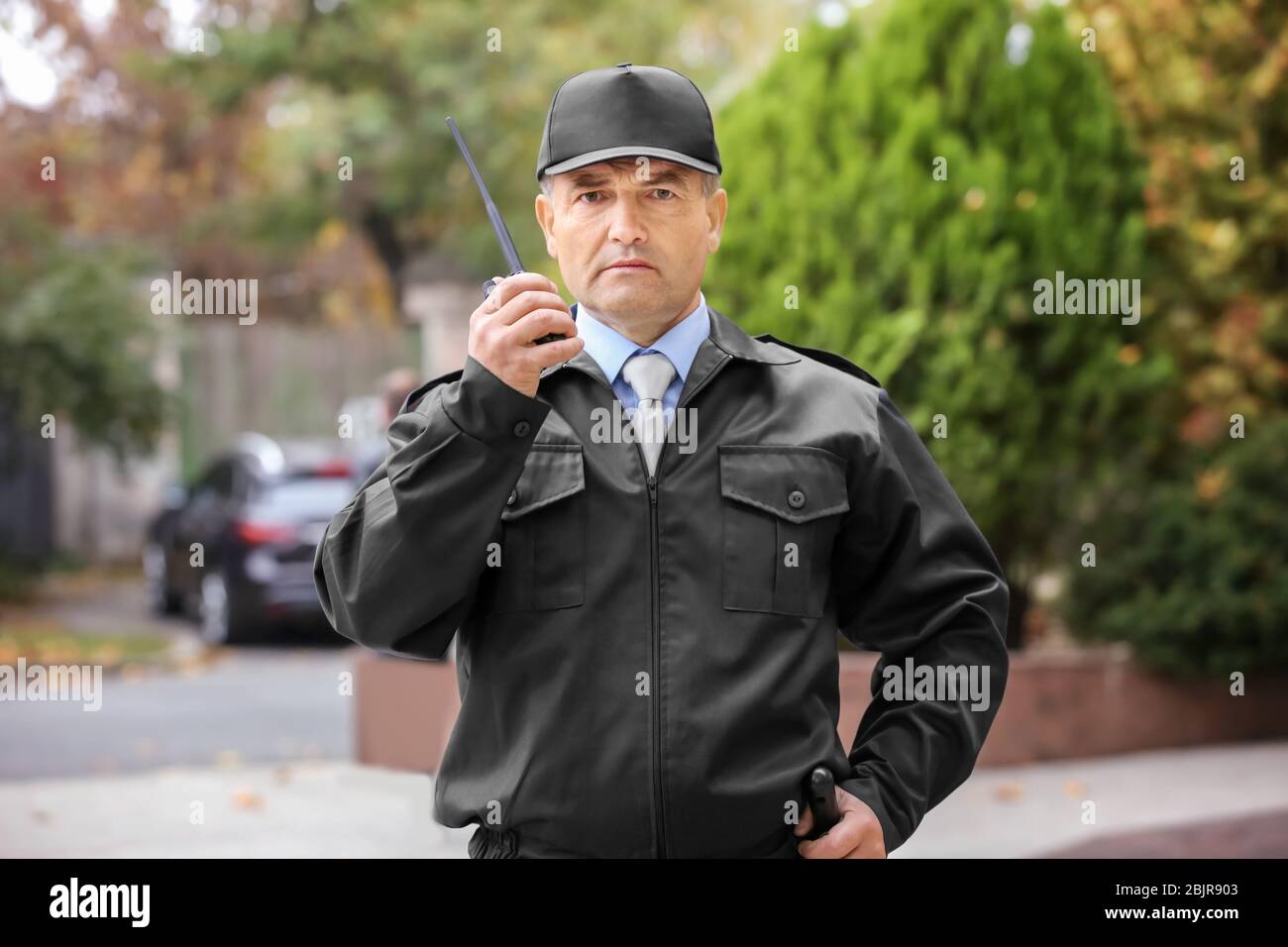 Male security guard using portable radio outdoors Stock Photo - Alamy