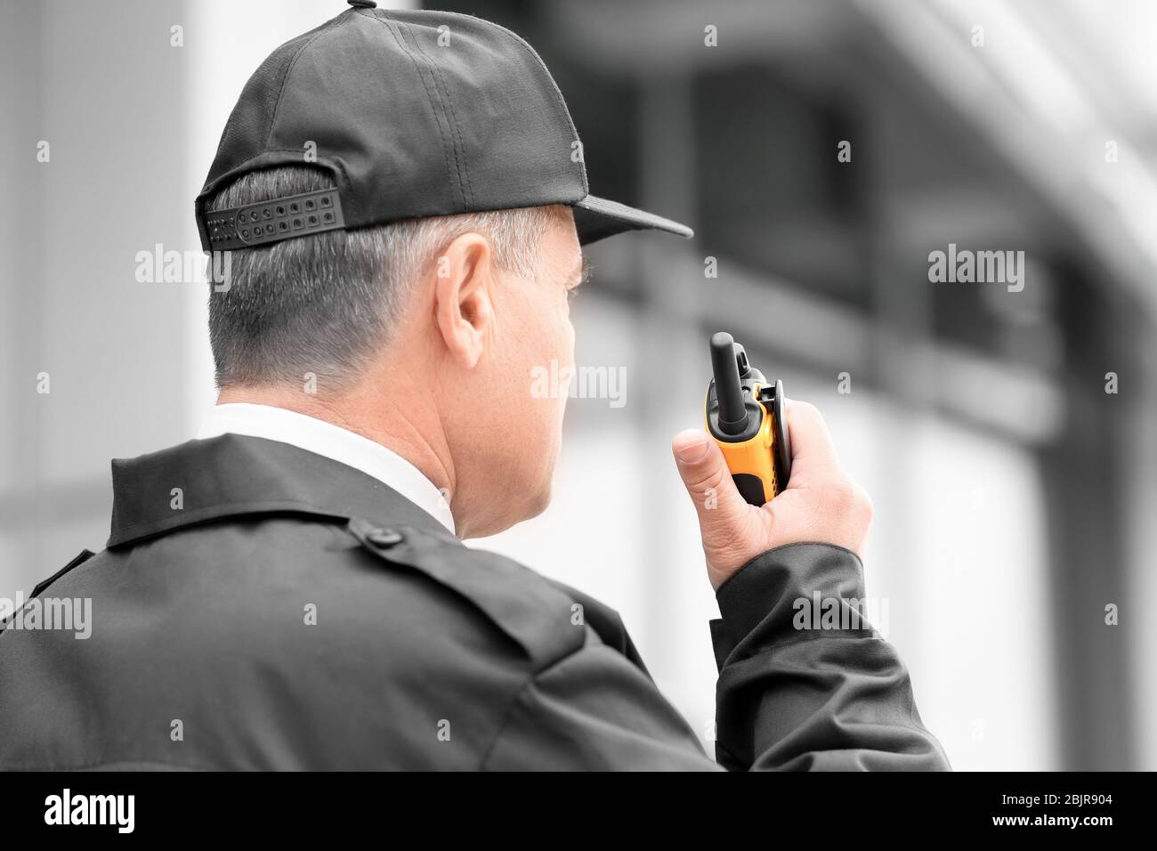 Male security guard using portable radio outdoors Stock Photo - Alamy
