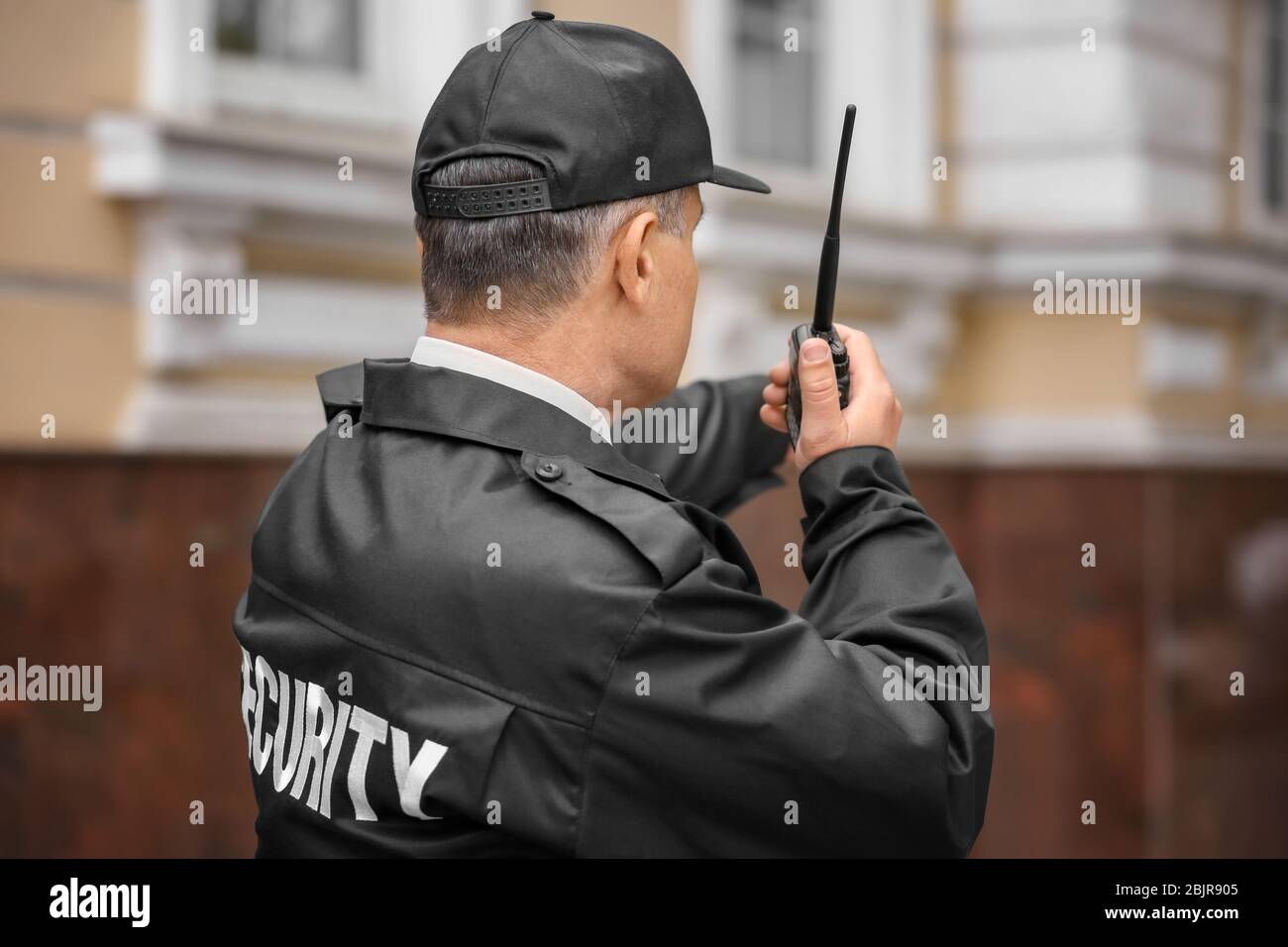 Male security guard using portable radio outdoors Stock Photo - Alamy