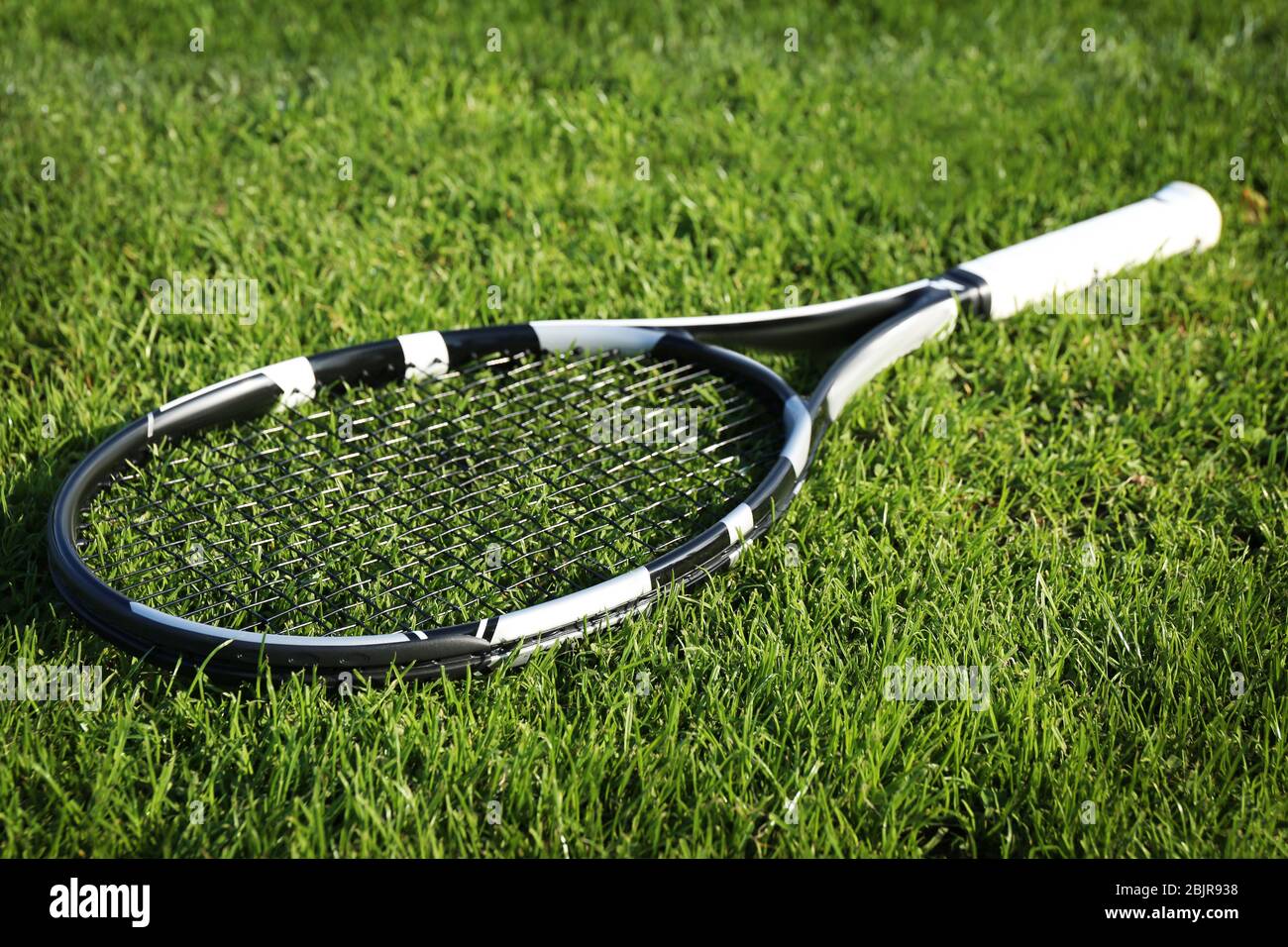 Modern tennis racket on green grass Stock Photo - Alamy