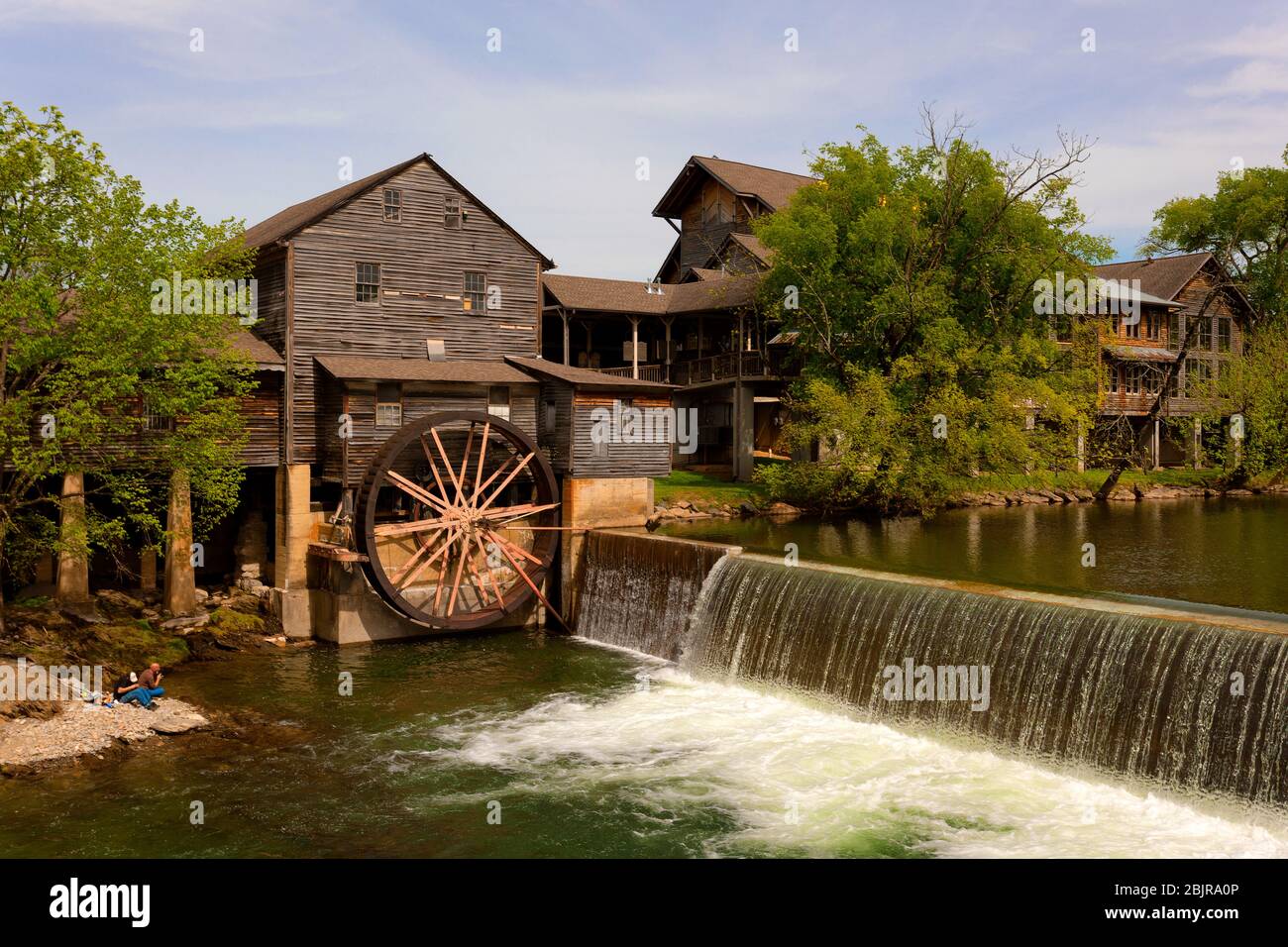 Pigeon Forge, Tennessee, USA - April 22,2020: Two men fish next to the Old Grist Mill, built in ...