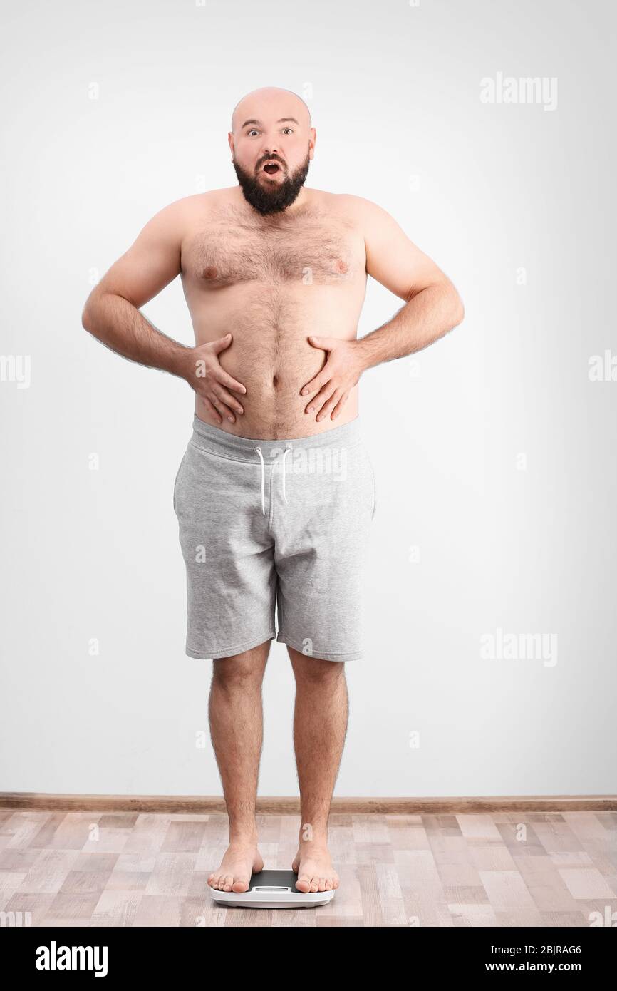 Overweight man measuring his weight using scales on floor Stock Photo ...