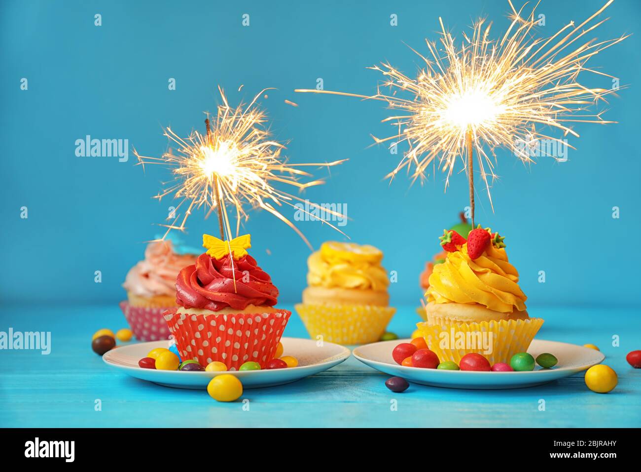 Festive bright cupcakes with sparklers on color background Stock Photo - Alamy