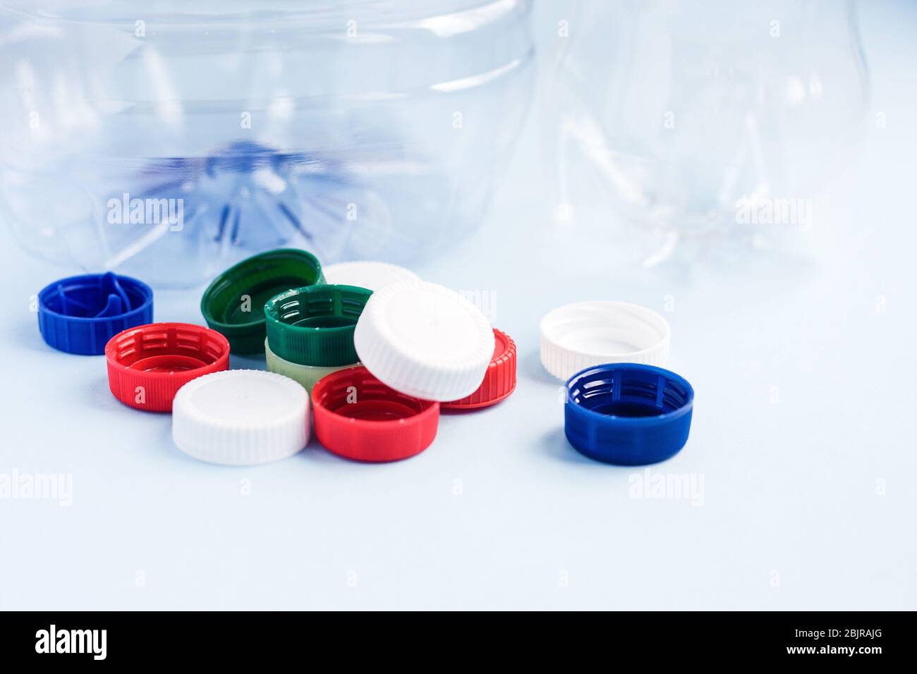 Colorful plastic caps against bottles. Plastic wrapping rubbish on blue ...