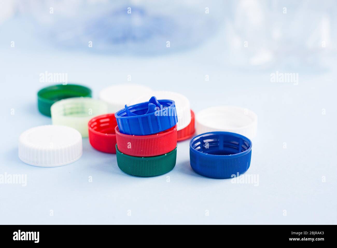 Colorful plastic caps against bottles. Plastic wrapping rubbish on blue ...