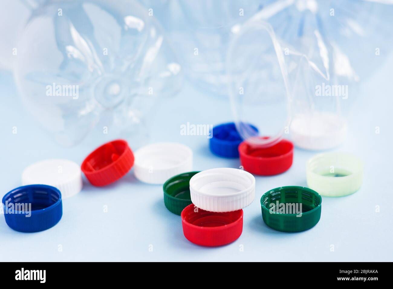 Colorful plastic caps against bottles. Plastic wrapping rubbish on blue ...