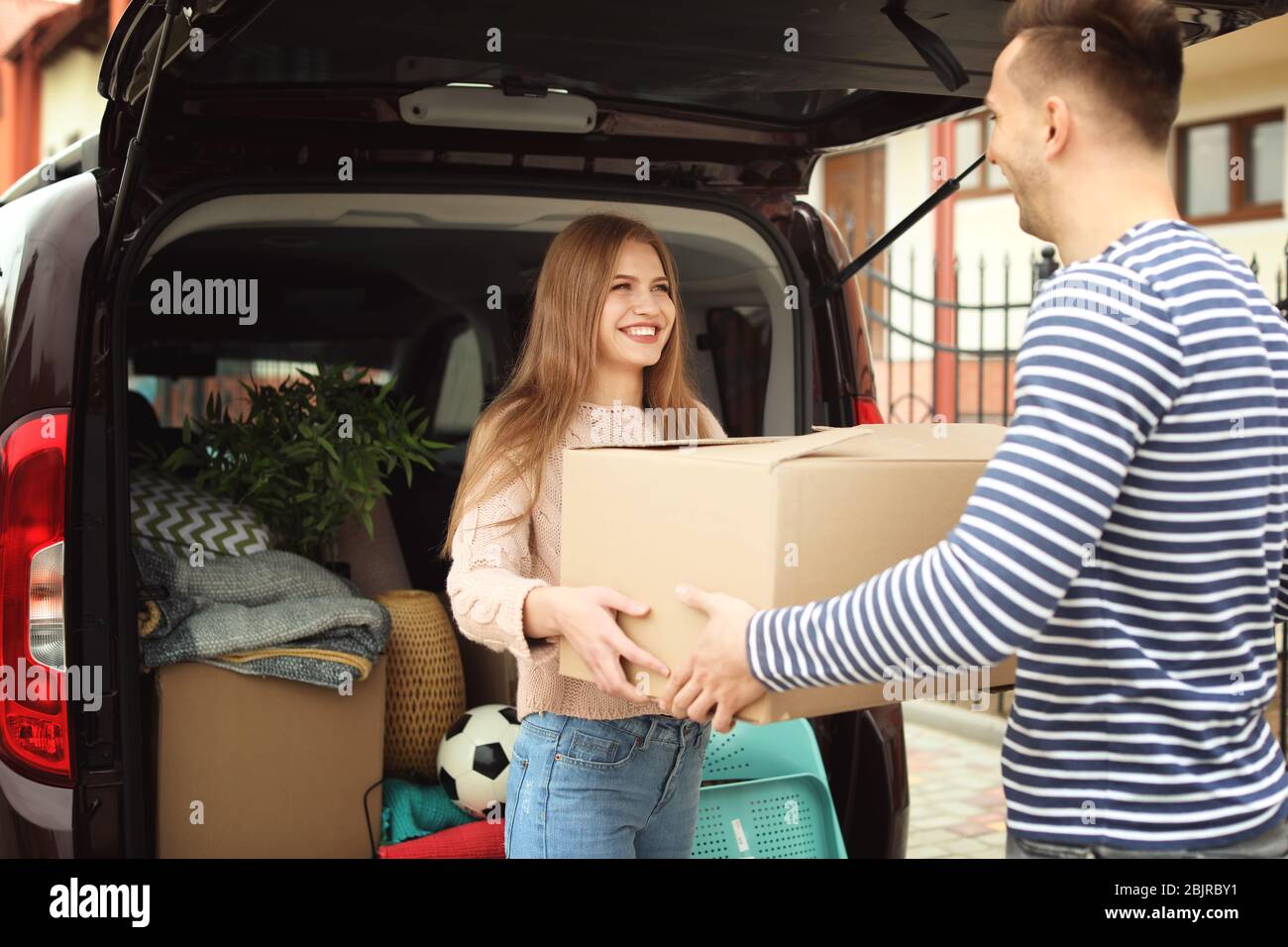 Young couple unloading boxes from their car on moving day Stock Photo ...