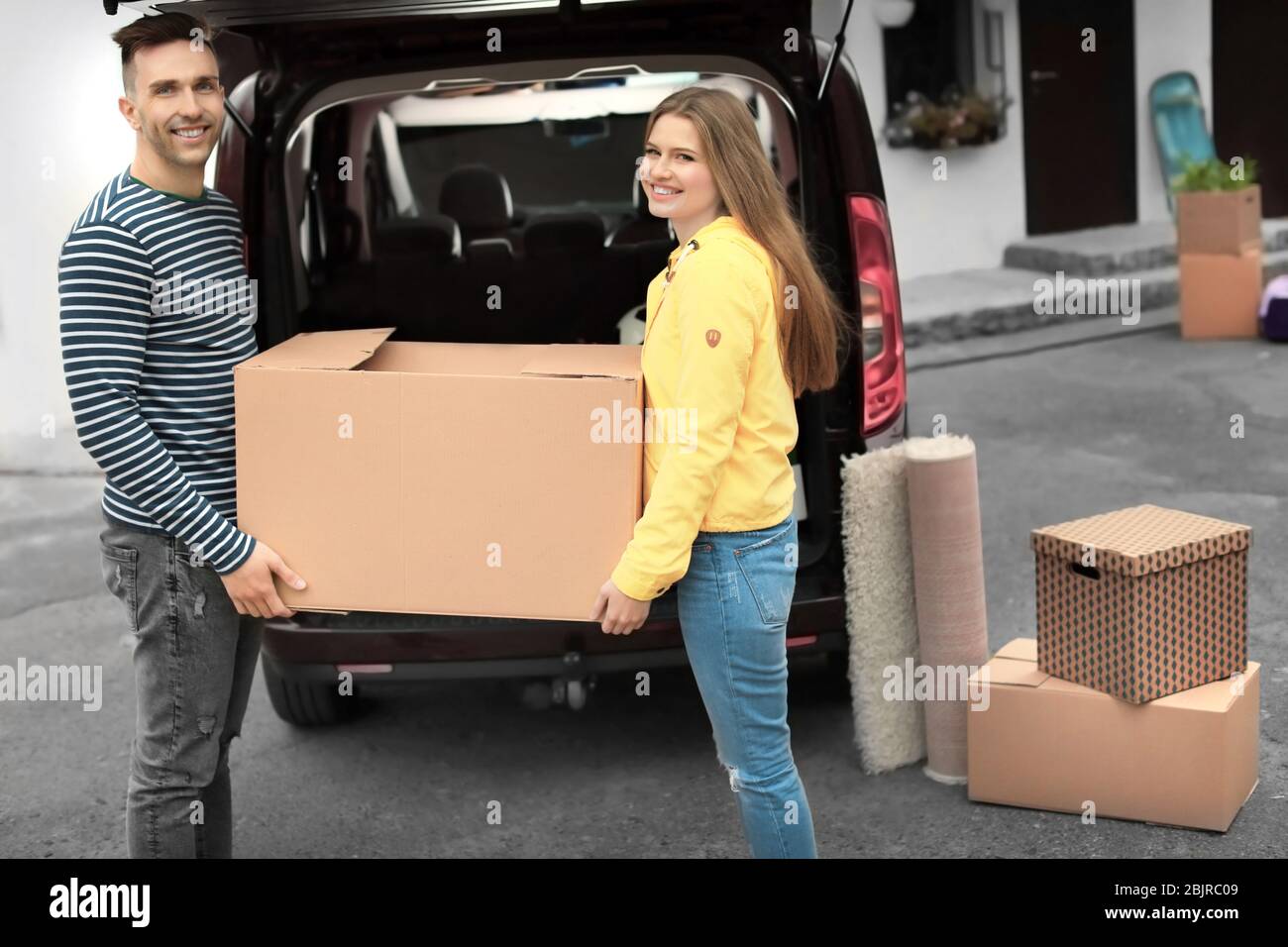 Young couple unloading boxes from their car on moving day Stock Photo ...