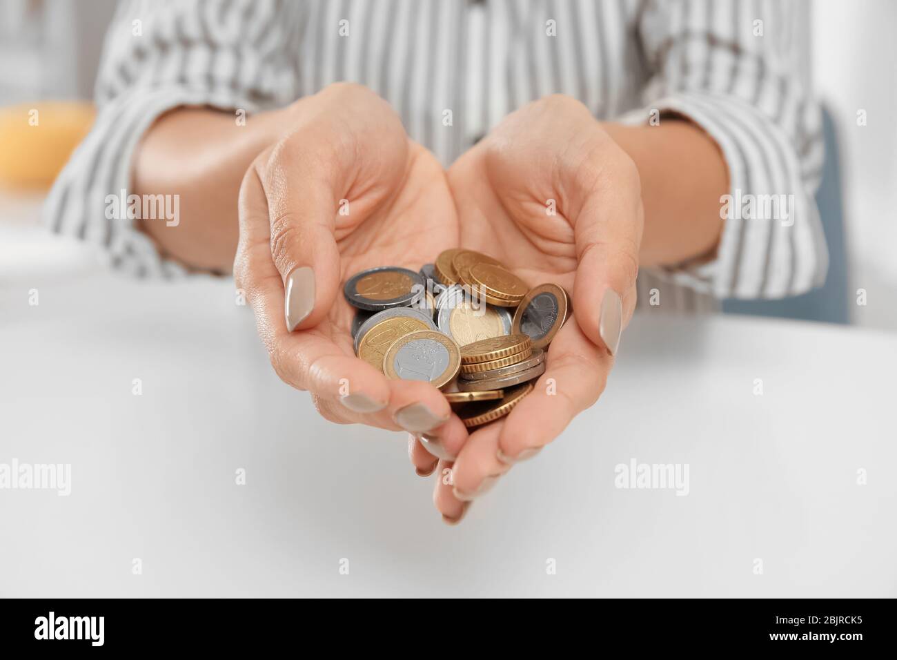 Woman holding handful of coins over table, closeup Stock Photo - Alamy