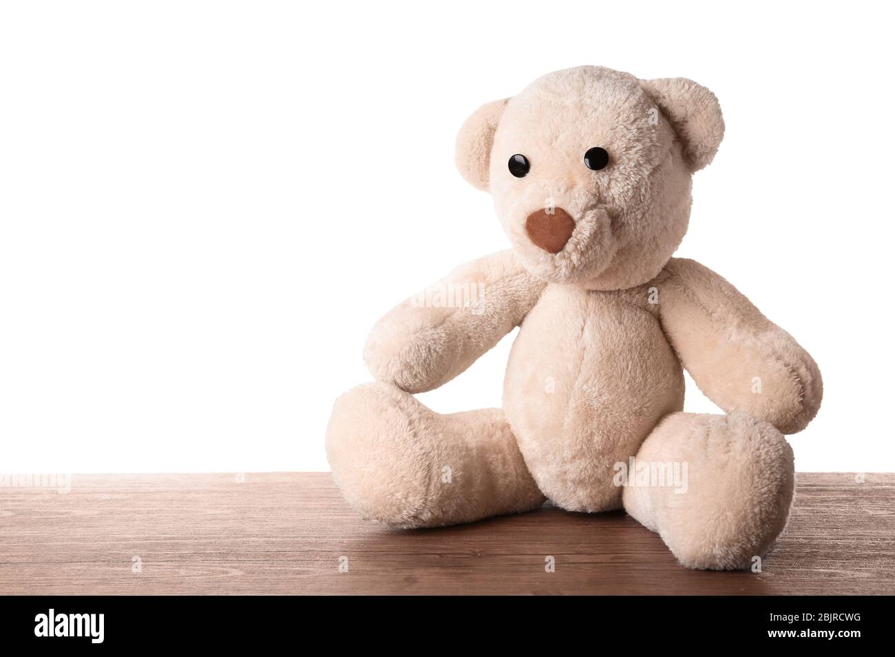 Cute teddy bear on table against white background Stock Photo - Alamy