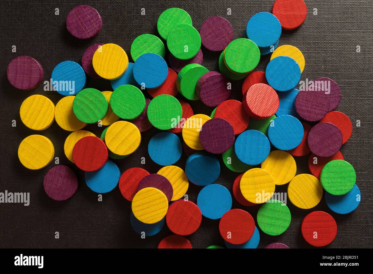 Round, wooden, multicolored, game chips on a black textured background ...