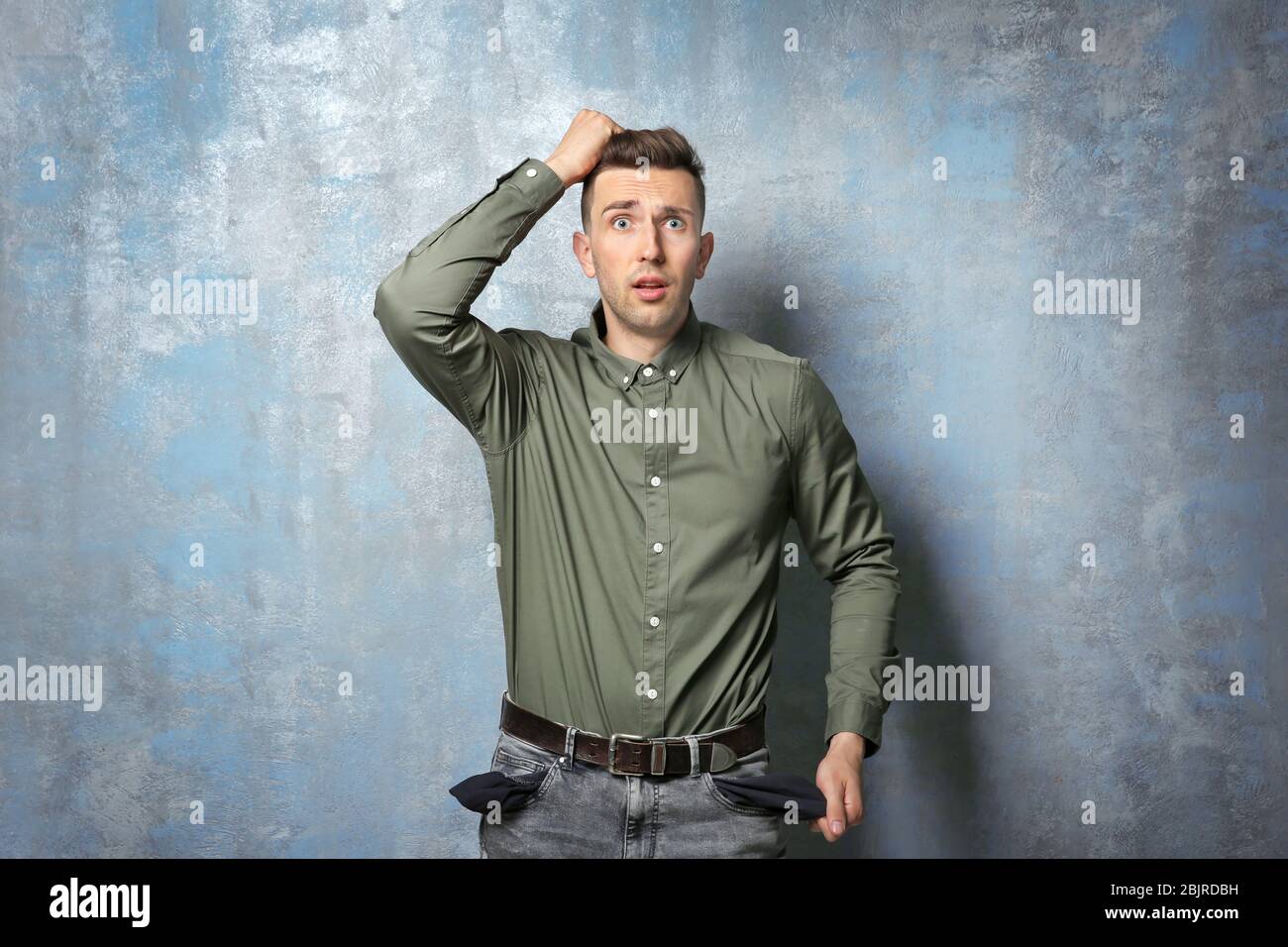 Sad man showing his empty pockets on grunge background Stock Photo - Alamy